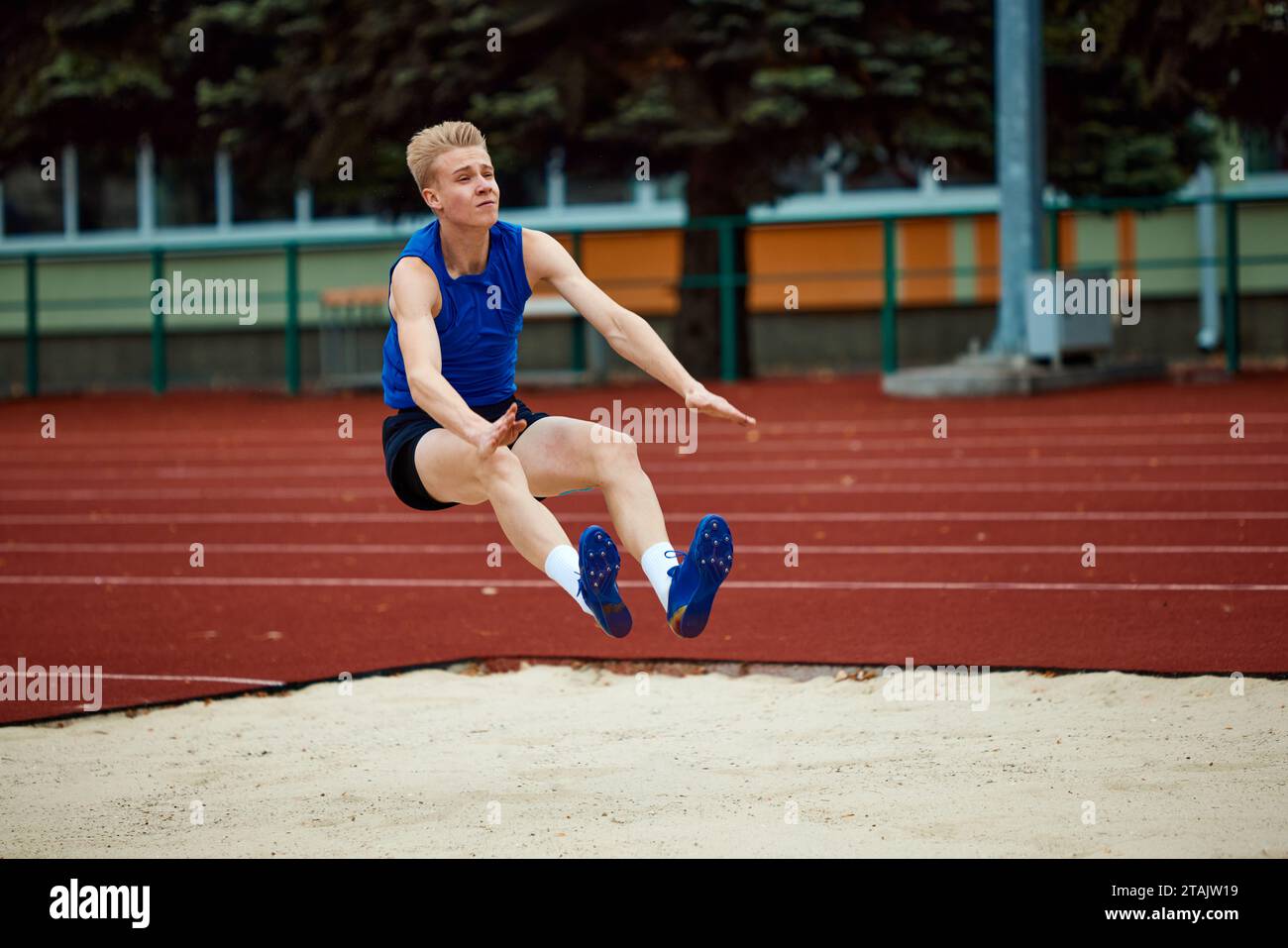 Precision and poise define athlete's descent into sand. Athletic man ...