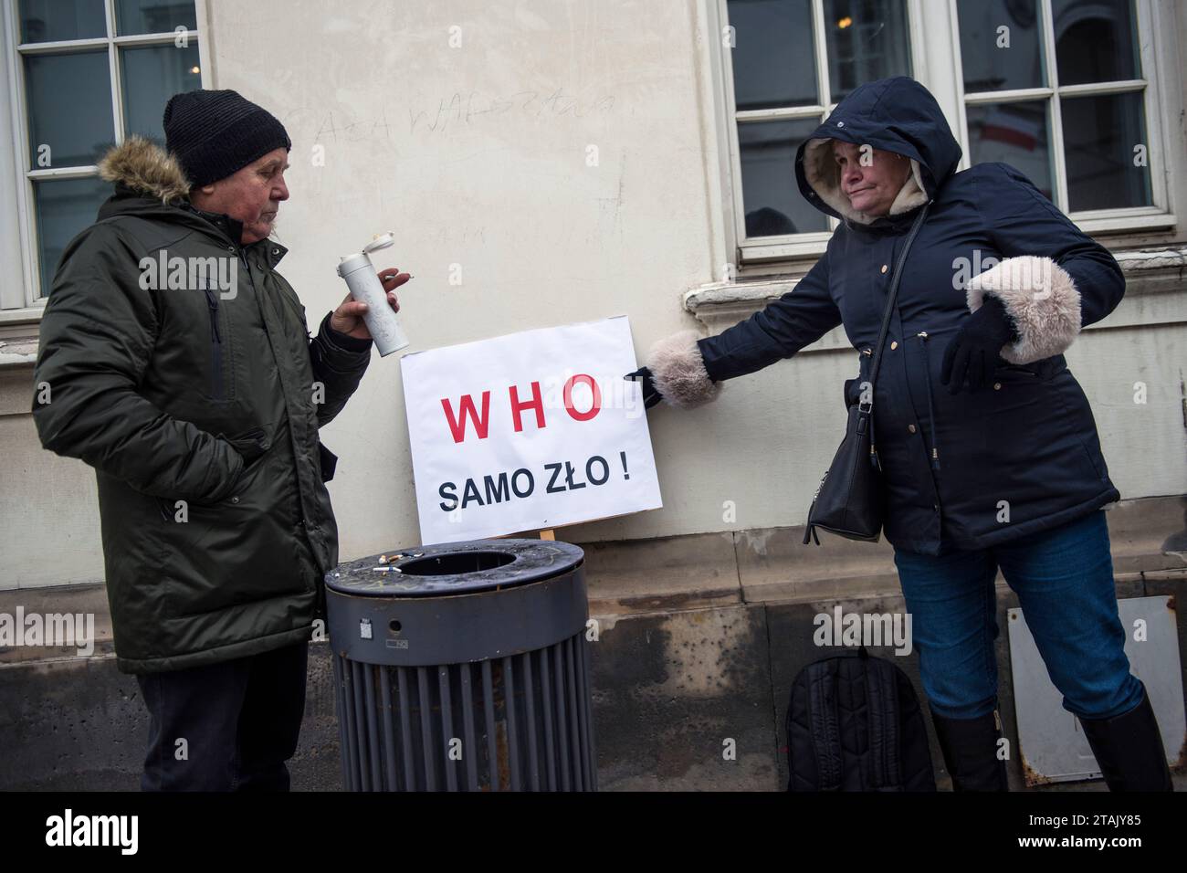 A woman puts a placard that says - WHO pure evil - next to a trash can ...