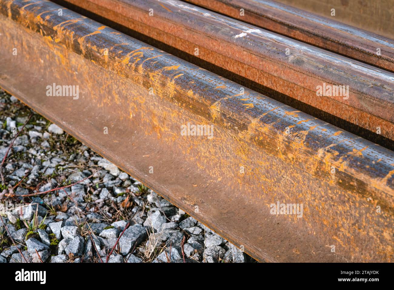 Old rusted railroad rails on the gravel ground, close up side view ...