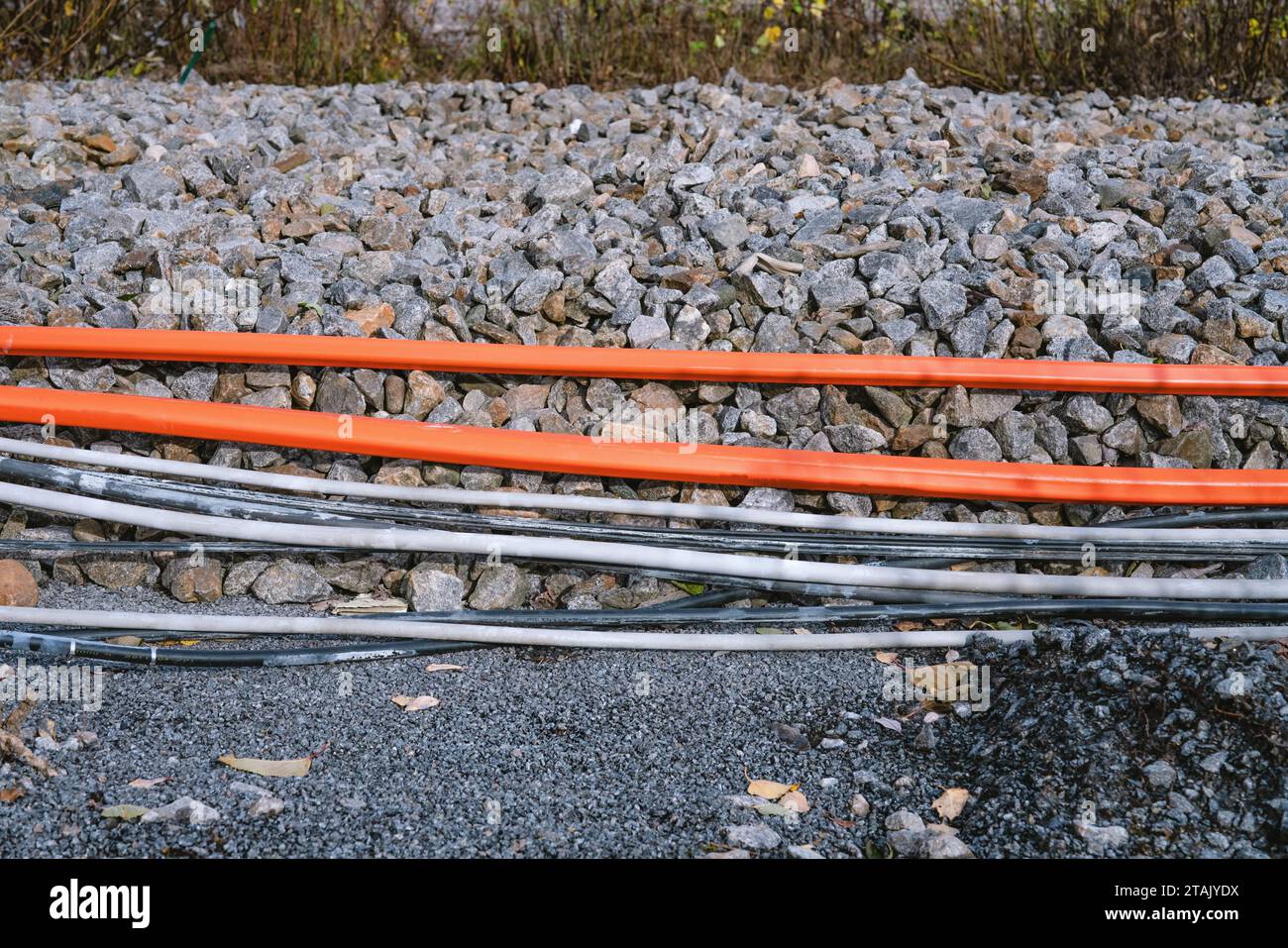 Parallel cables of different color and sizes on gravel ground beside ...