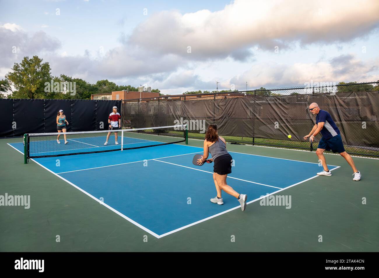 A male pickleball player hits a return to his opponents as his partner ...