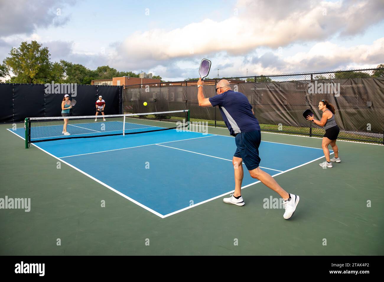 A male pickleball player serves as his partner watches on in a mix ...