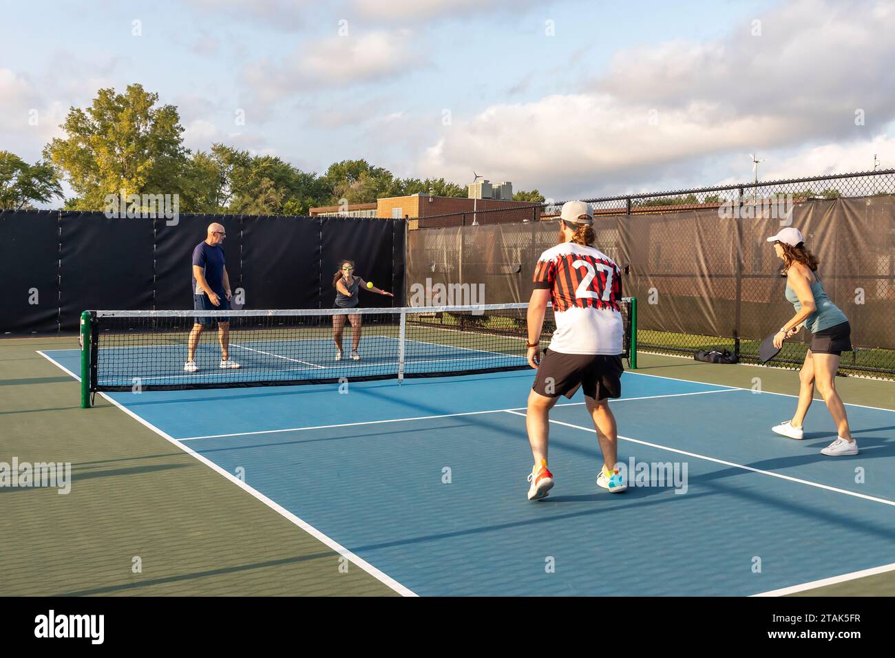 A female pickleball player returns a ball at the net as her opponents ...