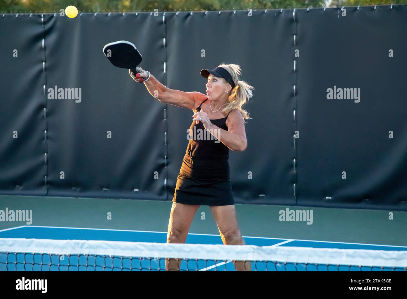 A female pickleball player returns a high ball at the net Stock Photo ...