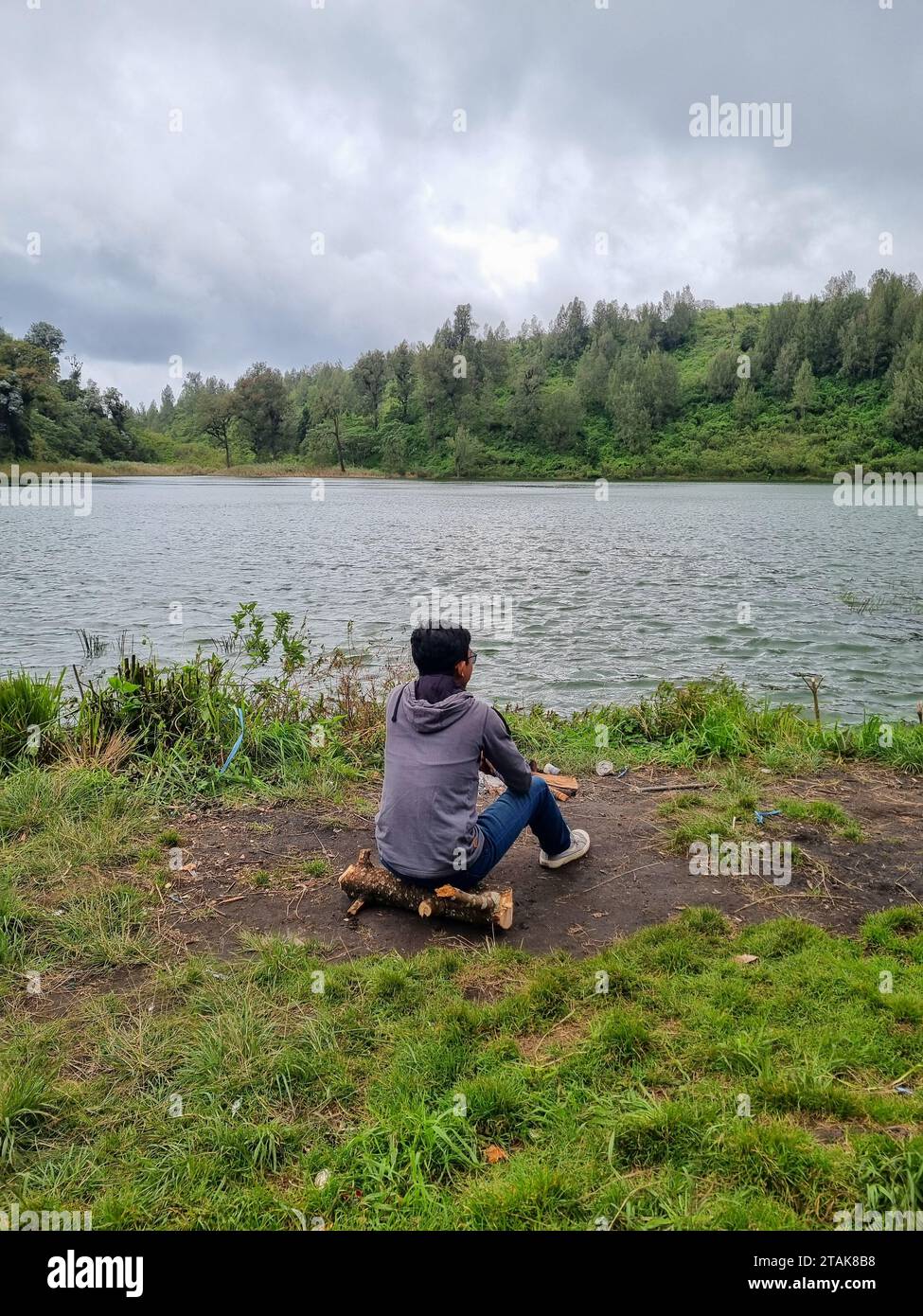 A man seems to enjoy the landscape view alongside the Ranu Regulo Lake ...