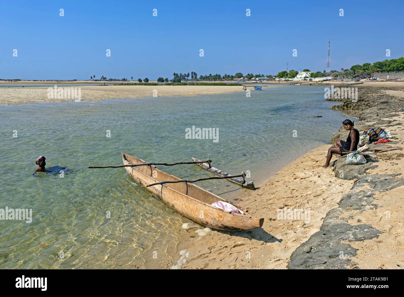 Single-outrigger canoe and two local Malagasy women on the beach at the ...