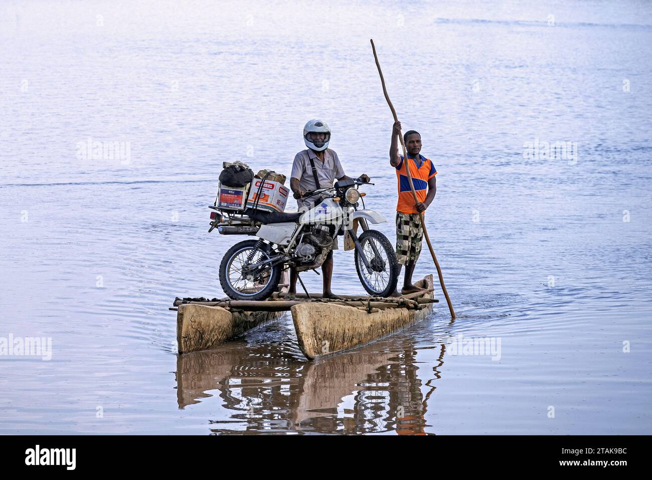 Motorcycle on primitive ferry, made of two joined dugout canoes ...