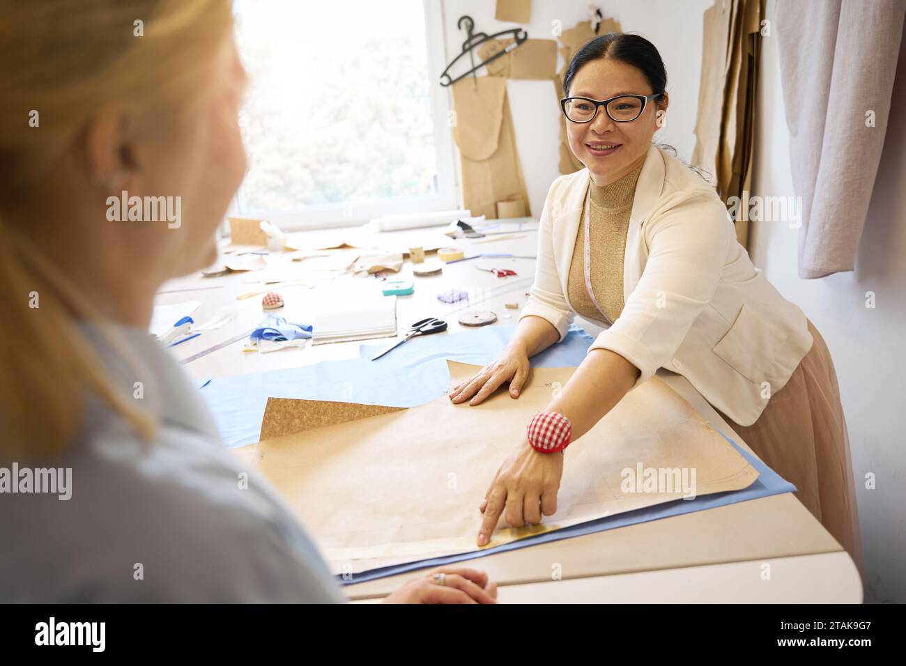 Tailoring master cuts fabric according to a pattern Stock Photo - Alamy