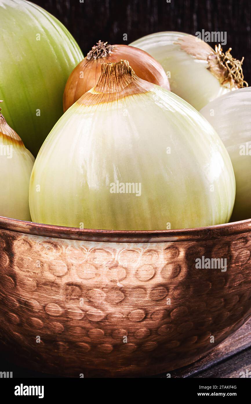 large Brazilian onions in rustic copper pot, shelled vegetables ...