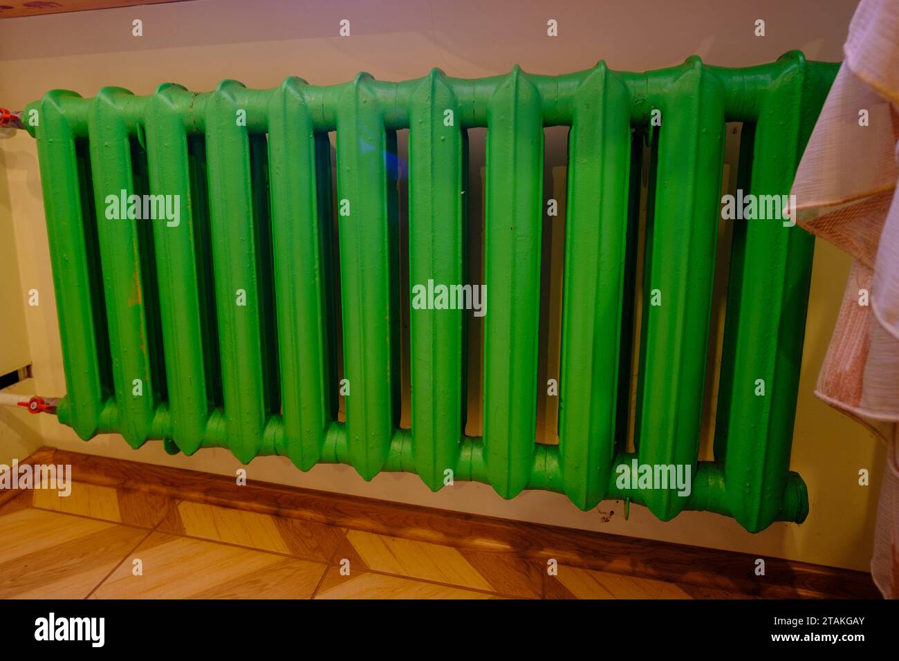 Old green color cast iron radiator heating on a background of an orange ...