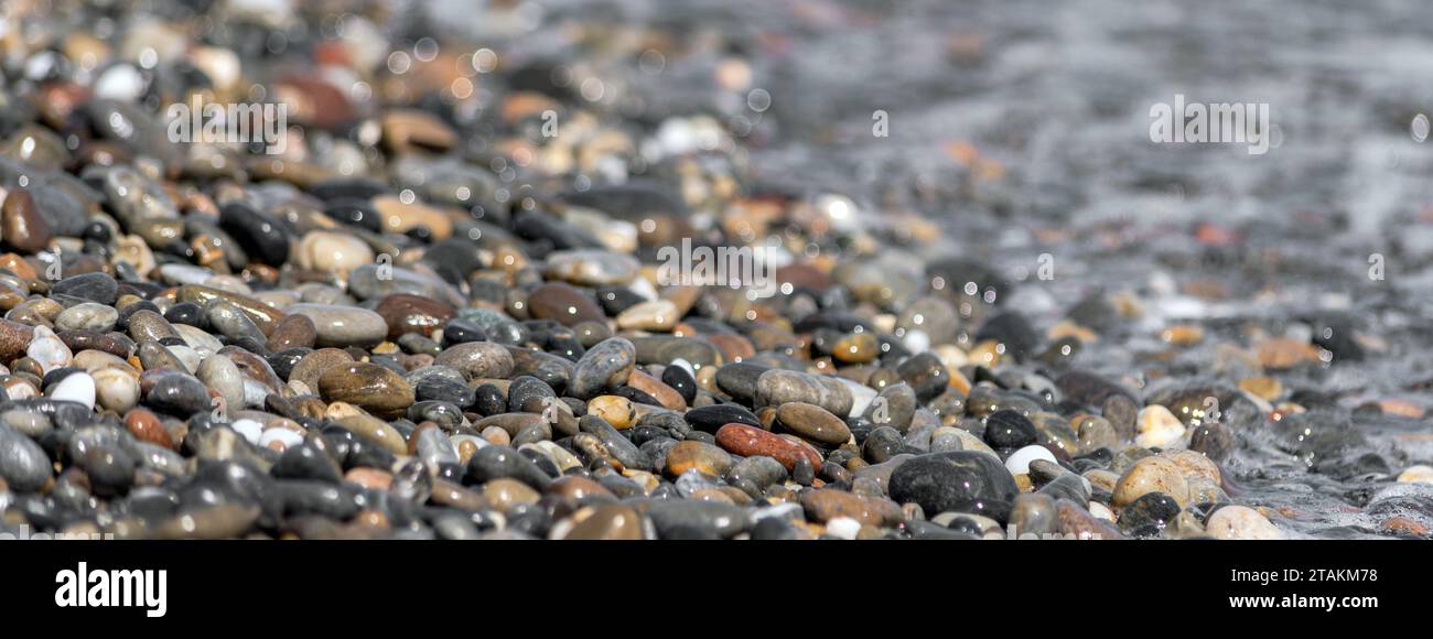Colored pebbles on the beach of Greece with the waves of the sea ...