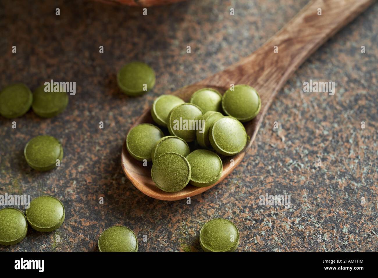 Green barley grass tablets on a wooden spoon. Healthy nutritional ...