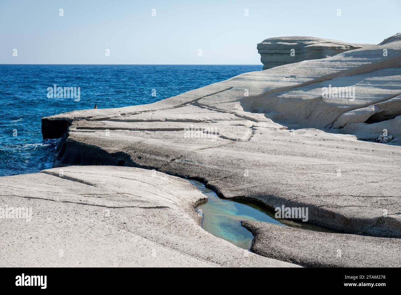 A scenic landscape with a large rock face surrounded by crystal-clear ...