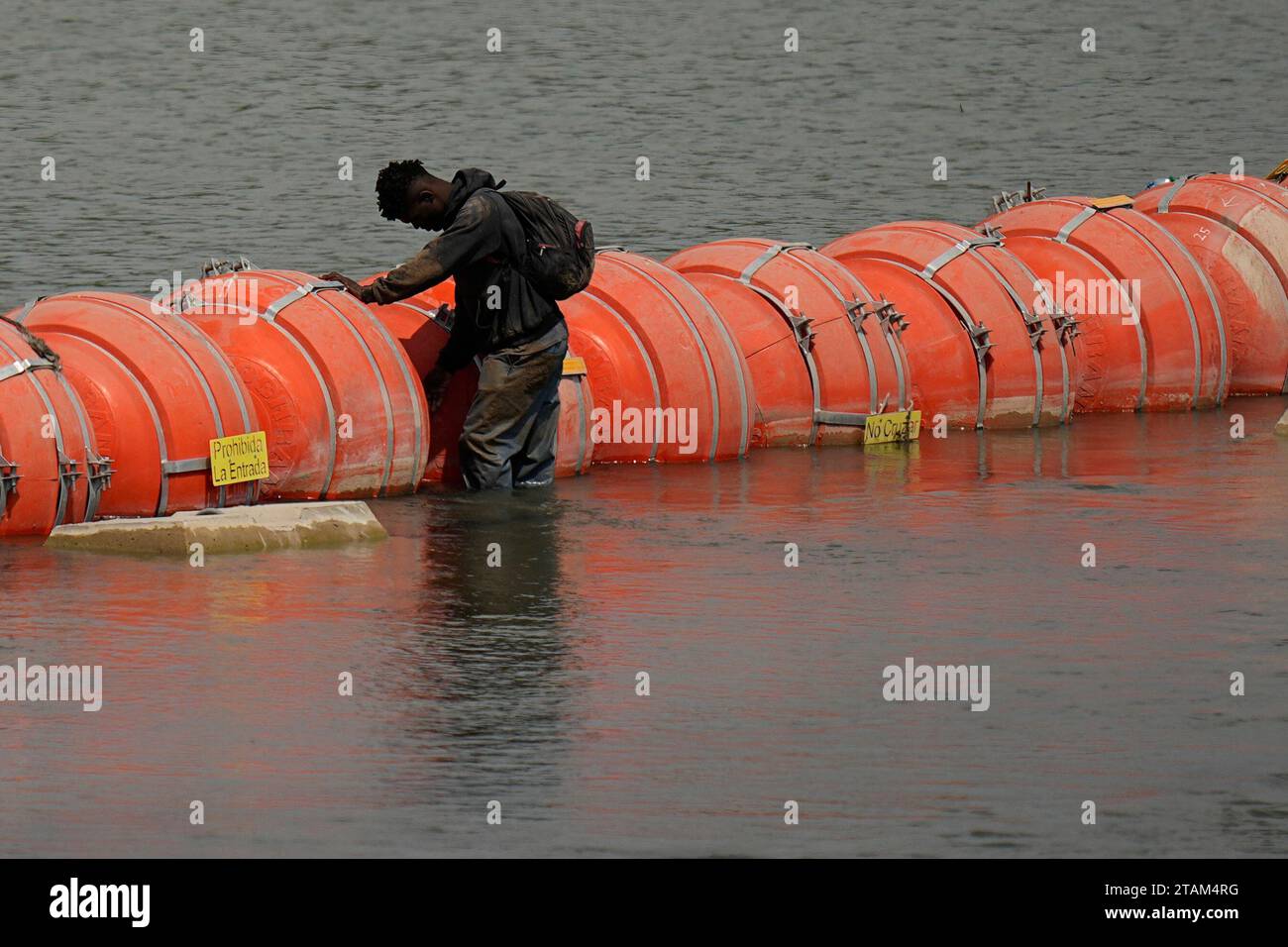 FILE - A migrant from Columbia stands at a floating buoy barrier as he ...