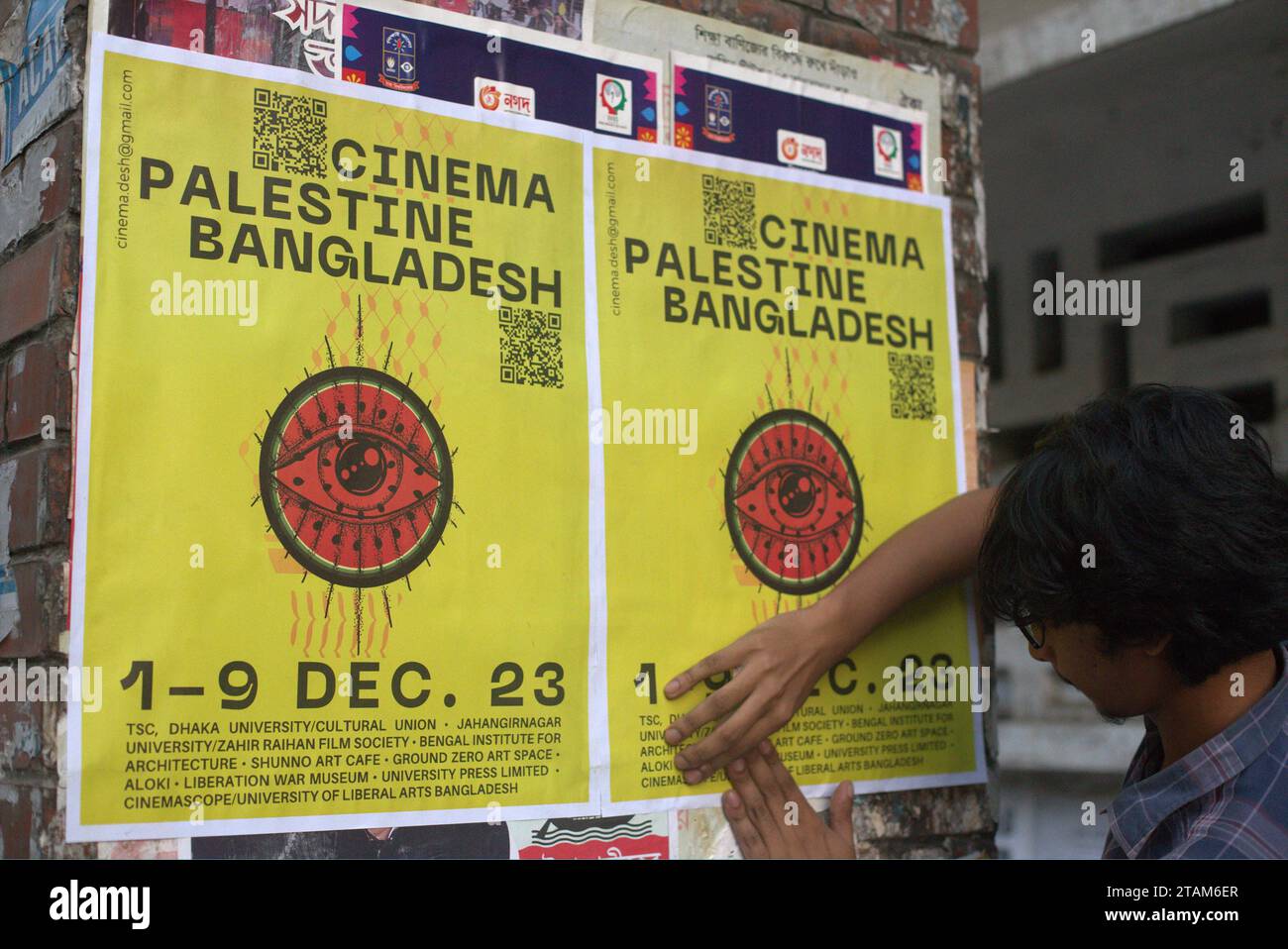 Dhaka, Bangladesh. 2nd Dec, 2023. An activist puts a cinema screening poster on a wall at Dhaka ...