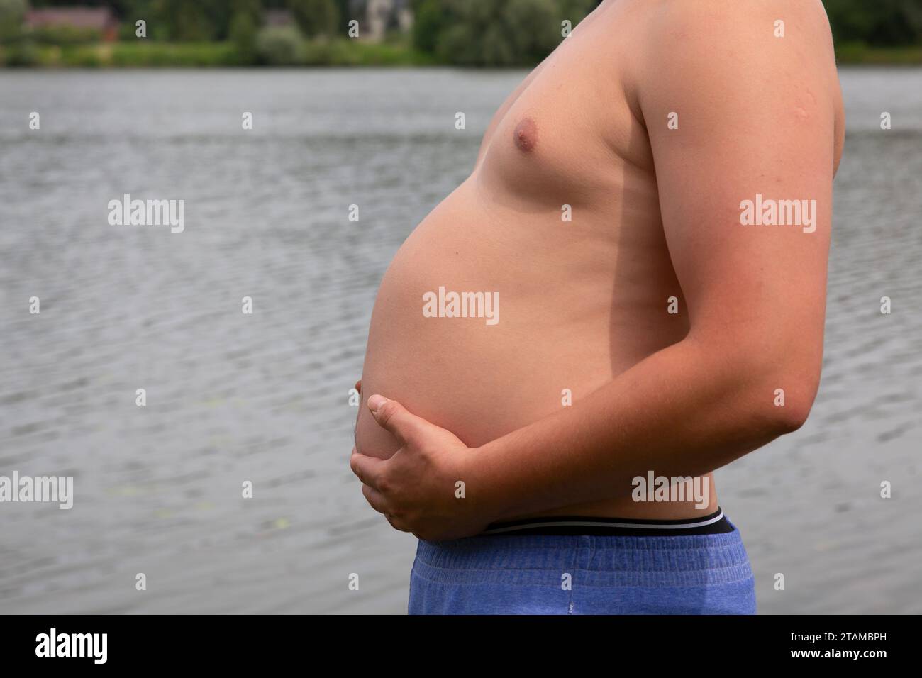 Fat man with big belly in the park. Close-up Stock Photo - Alamy