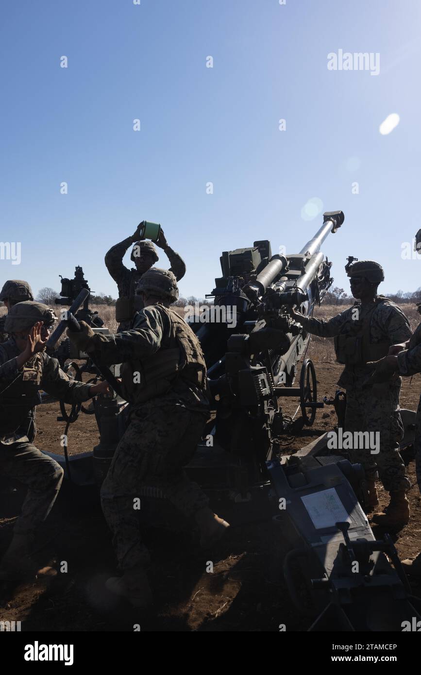 U.S. Marines use a ramming staff to set a round in an M777 Howitzer ...