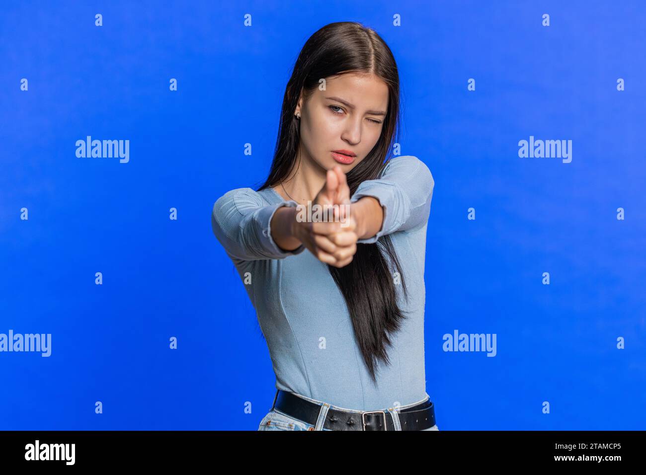 Caucasian young woman pointing around with finger gun gesture, looking ...