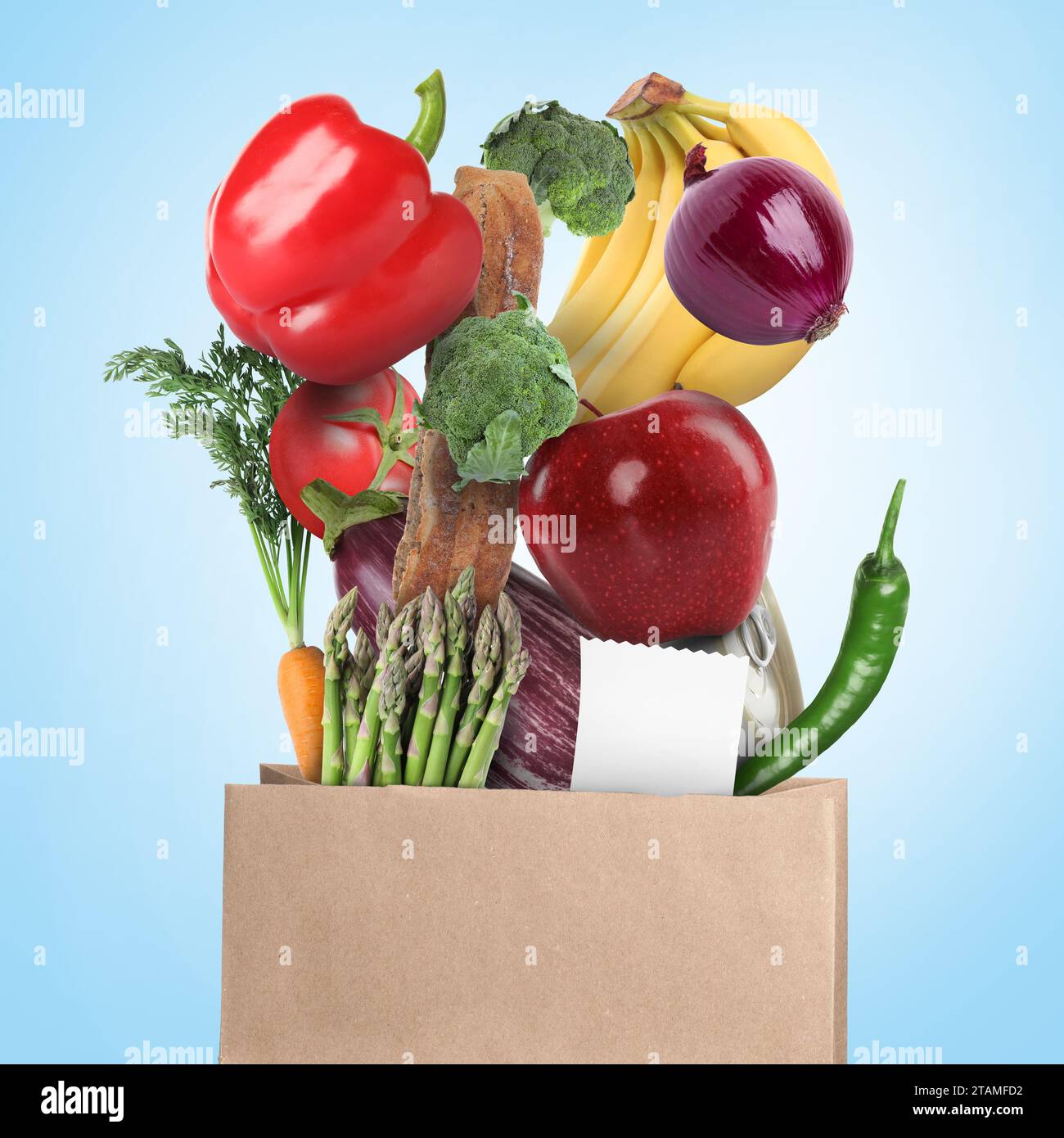 Different food products falling into paper bag on light blue background ...