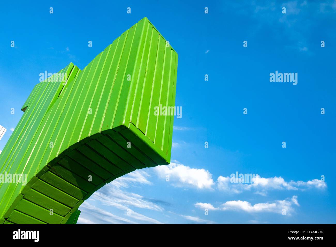 A curved green wooden arch seen from below against a blue sky ...