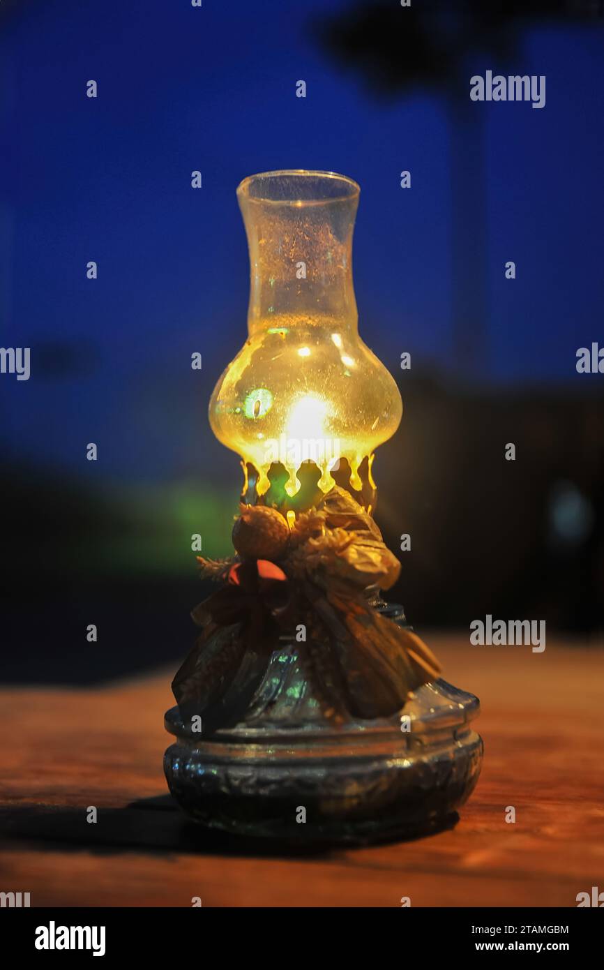 An oil lamp is burning on a table at night with a blurred background ...