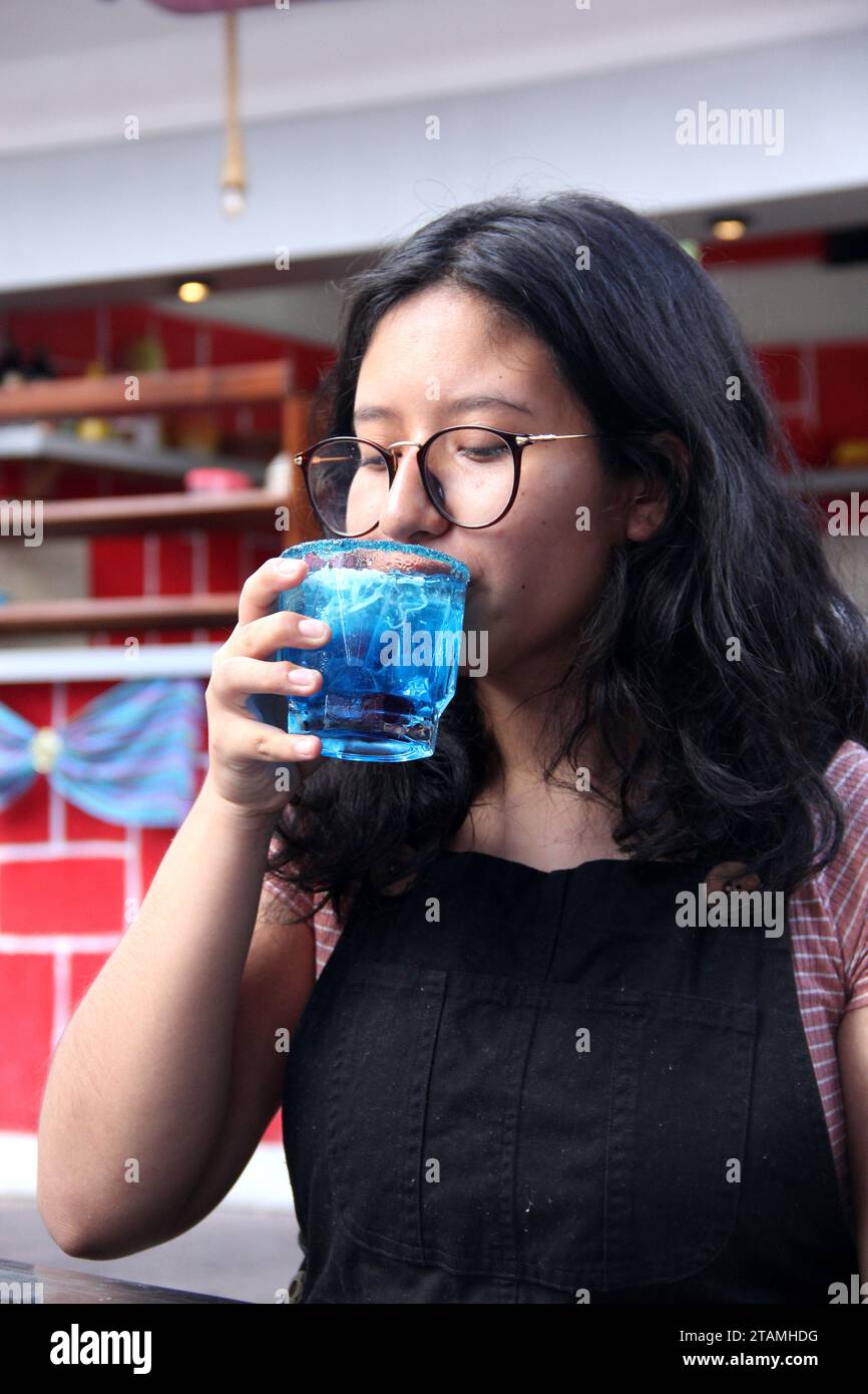 Young brunette Latina teenager woman drinks a blue colored Azulito ...
