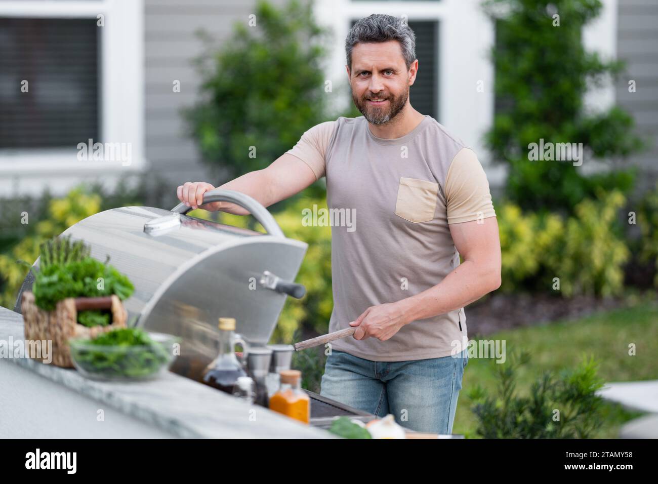 Handsome 40s man preparing barbecue. Male cook cooking meat on barbecue ...