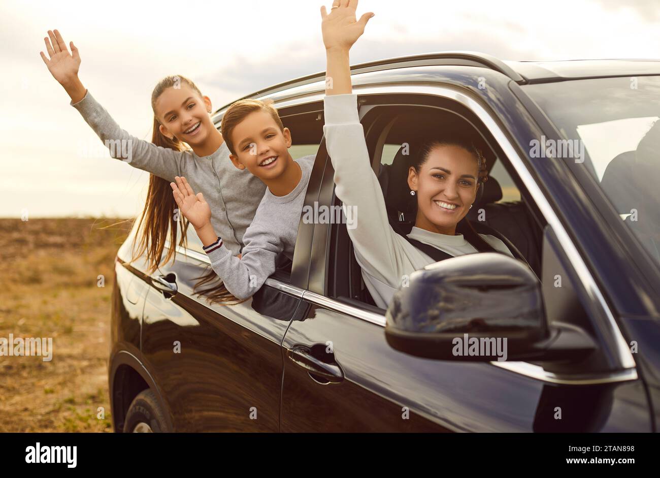 Happy family waving hand sitting in car traveling by automobile ...