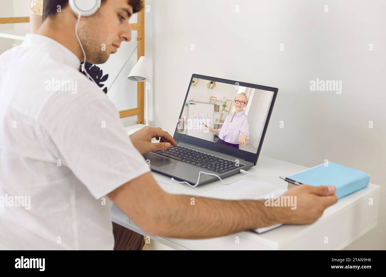 Adult student taking notes during his online lesson with a remote ...
