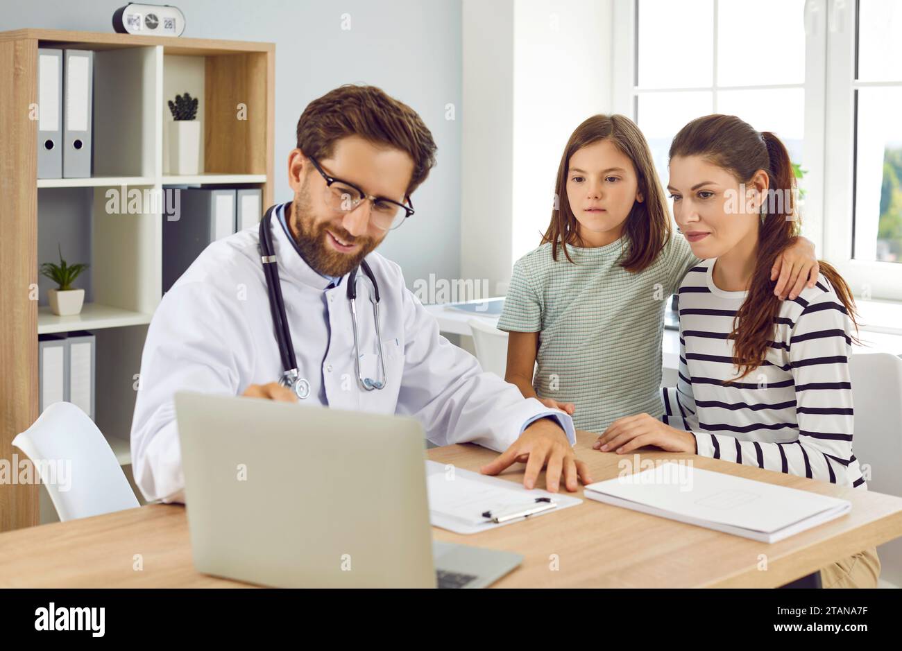 Family doctor talking to mother and child and showing diagnostic ...