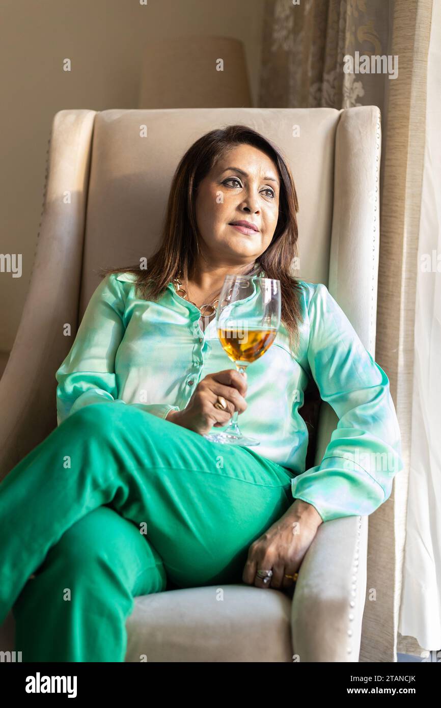 indian woman in casual clothes sitting on wing chair look away relaxing ...