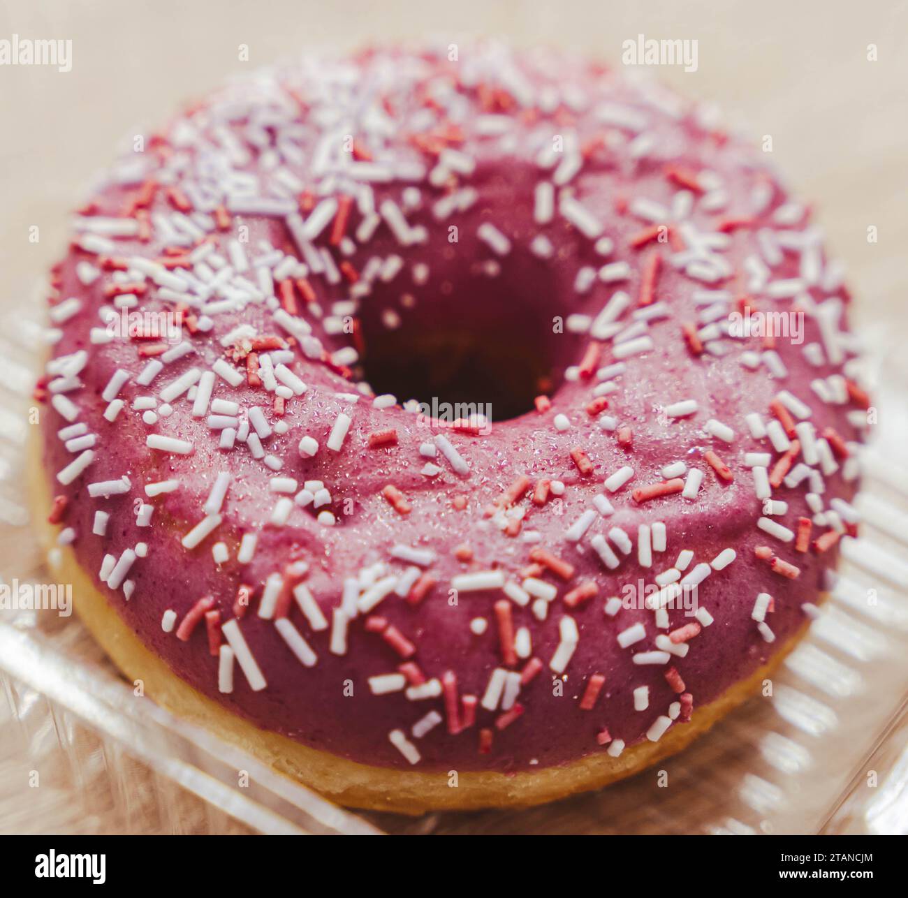 Close-up of a tempting pink doughnut topped with rainbow sprinkles, a ...