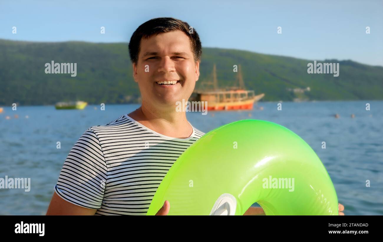 Young man inflating an inflatable swimming ring for his kids on a beach ...