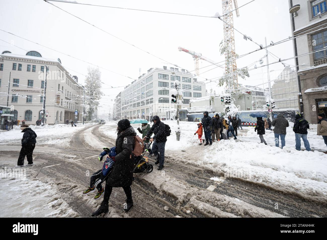 Munich, Germany. 02nd Dec, 2023. Travelers cross a snow-covered street ...