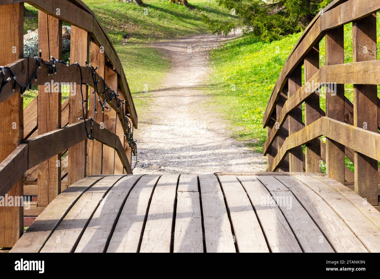 arched boardwalk of wooden planks with a path behind it leading to the ...