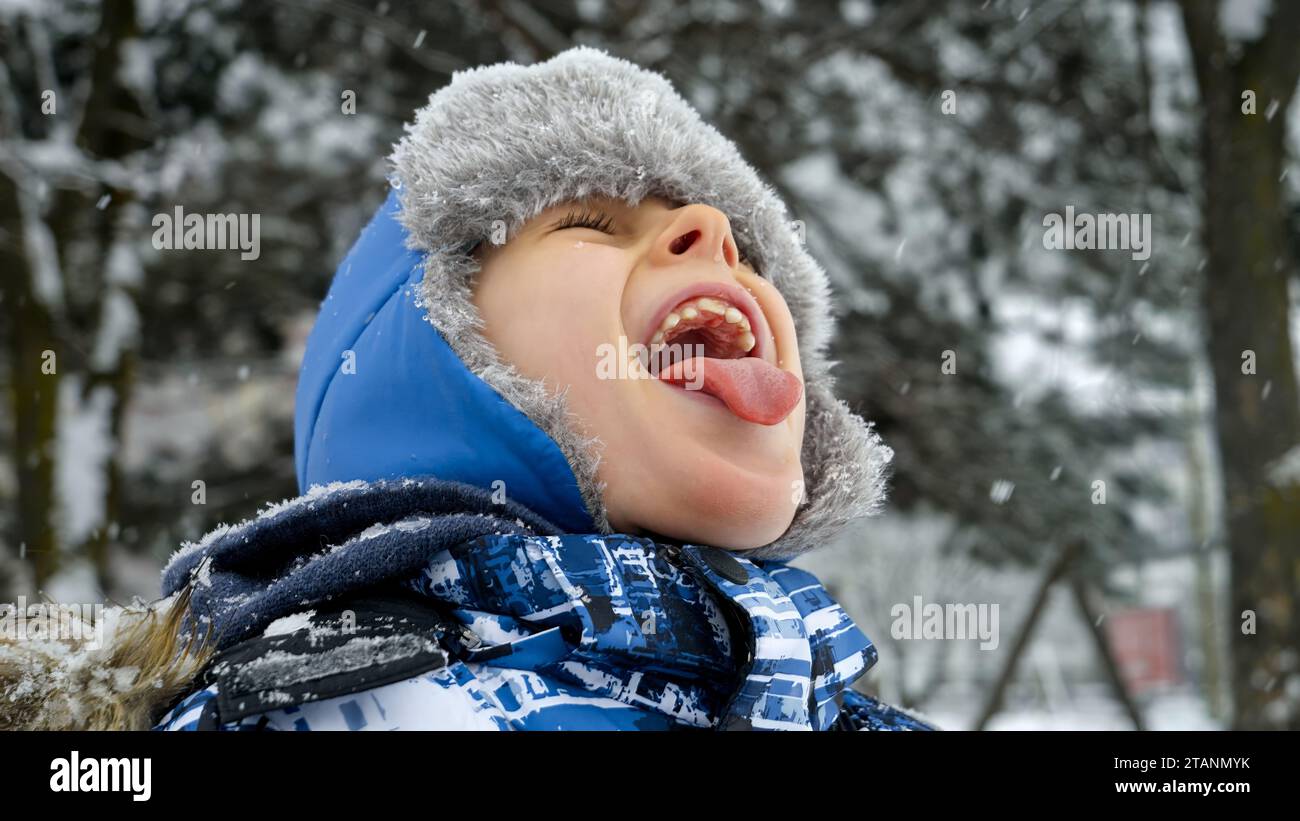 Portrait of boy joyfully catching snowflakes with his tongue during a ...