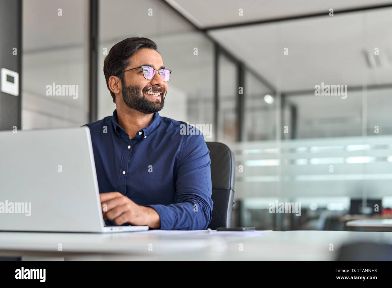 Happy Indian business man ceo executive looking away working on laptop ... Happy Indian business man ceo executive looking away working on laptop ...