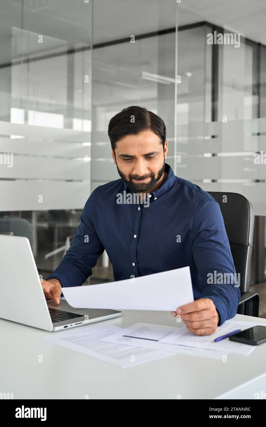 Busy Indian business man reading financial document using computer ...
