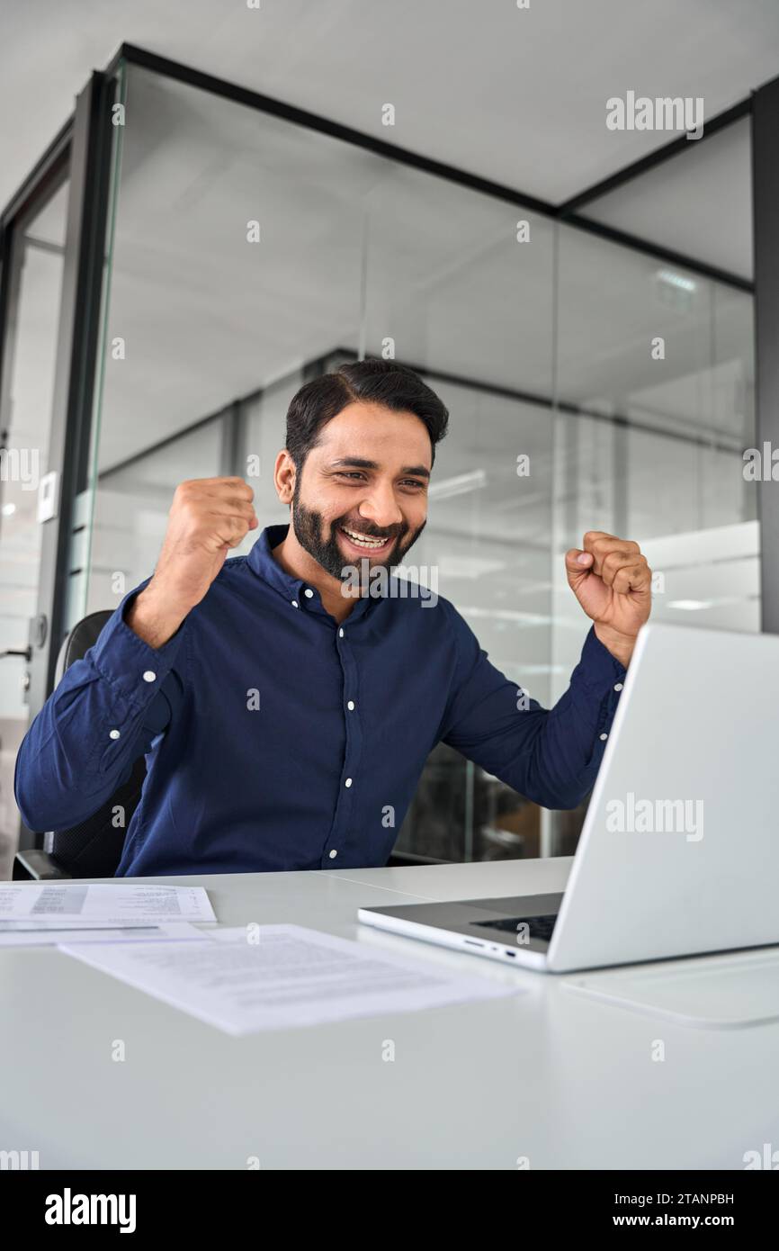 Happy professional Indian business man celebrating win using laptop at ...