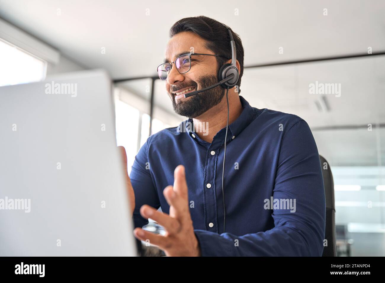 Smiling Indian call center agent in headset working in customer support ...