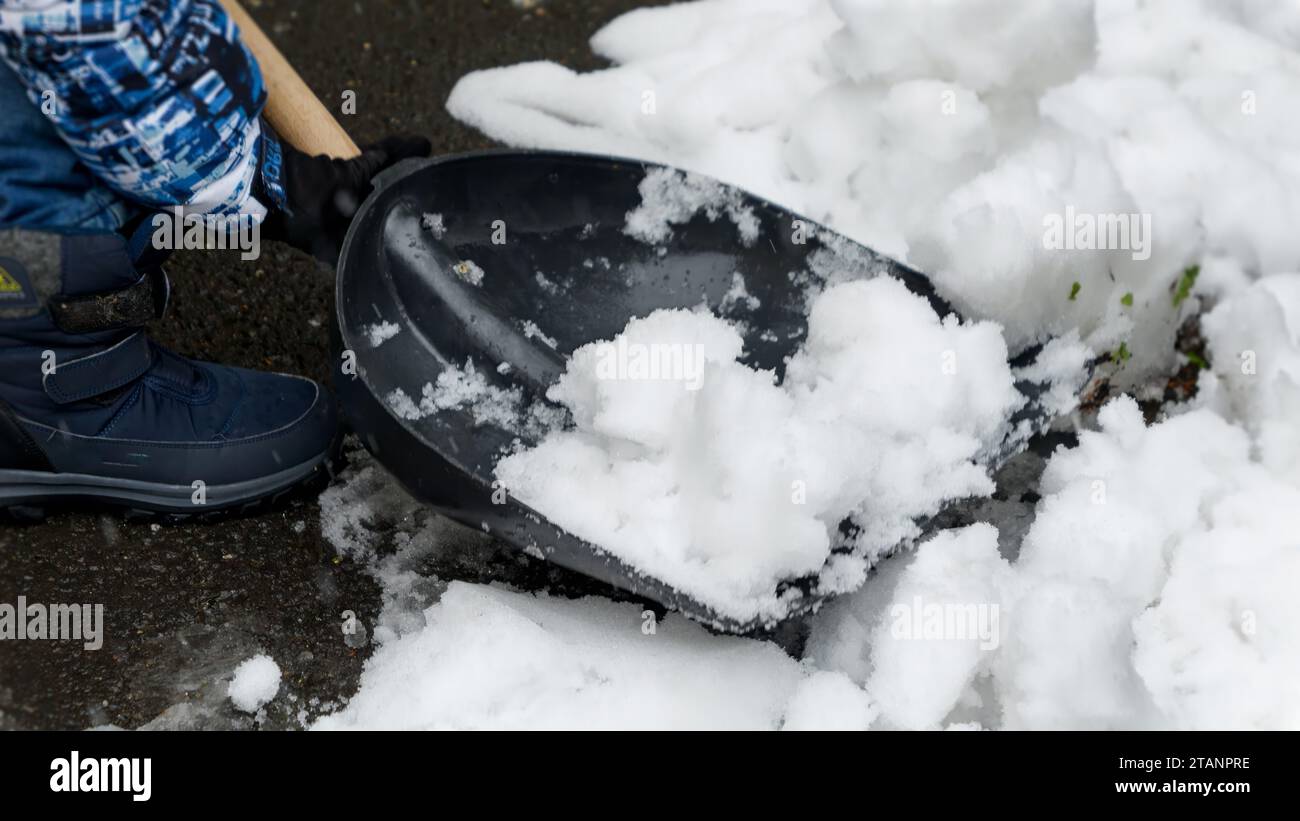 Young boy is shoveling snow from the backyard or walkway with a shovel ...