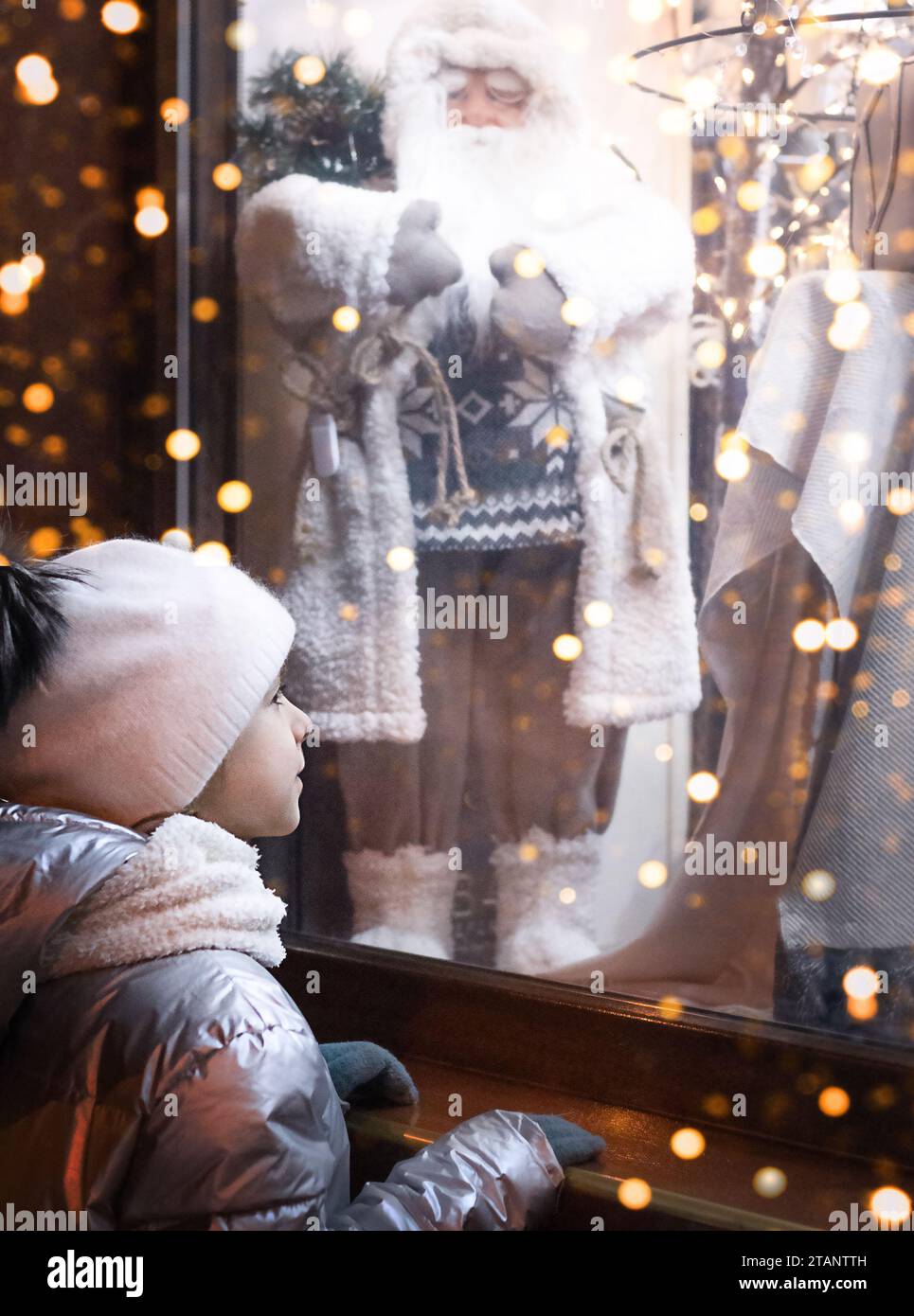 Girl looking out the window at Christmas decorations in a store ...