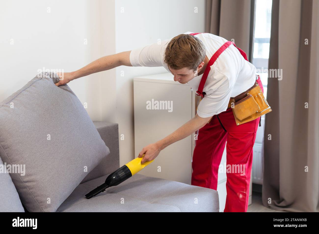 Handsome young man cleaning furniture. Process of deep furniture ...