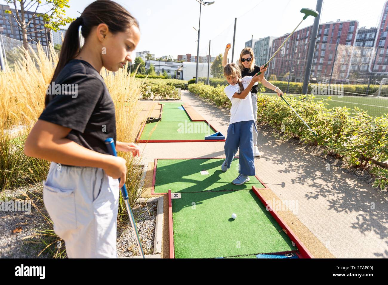 Cute school girl playing mini golf with family. Happy toddler child ...