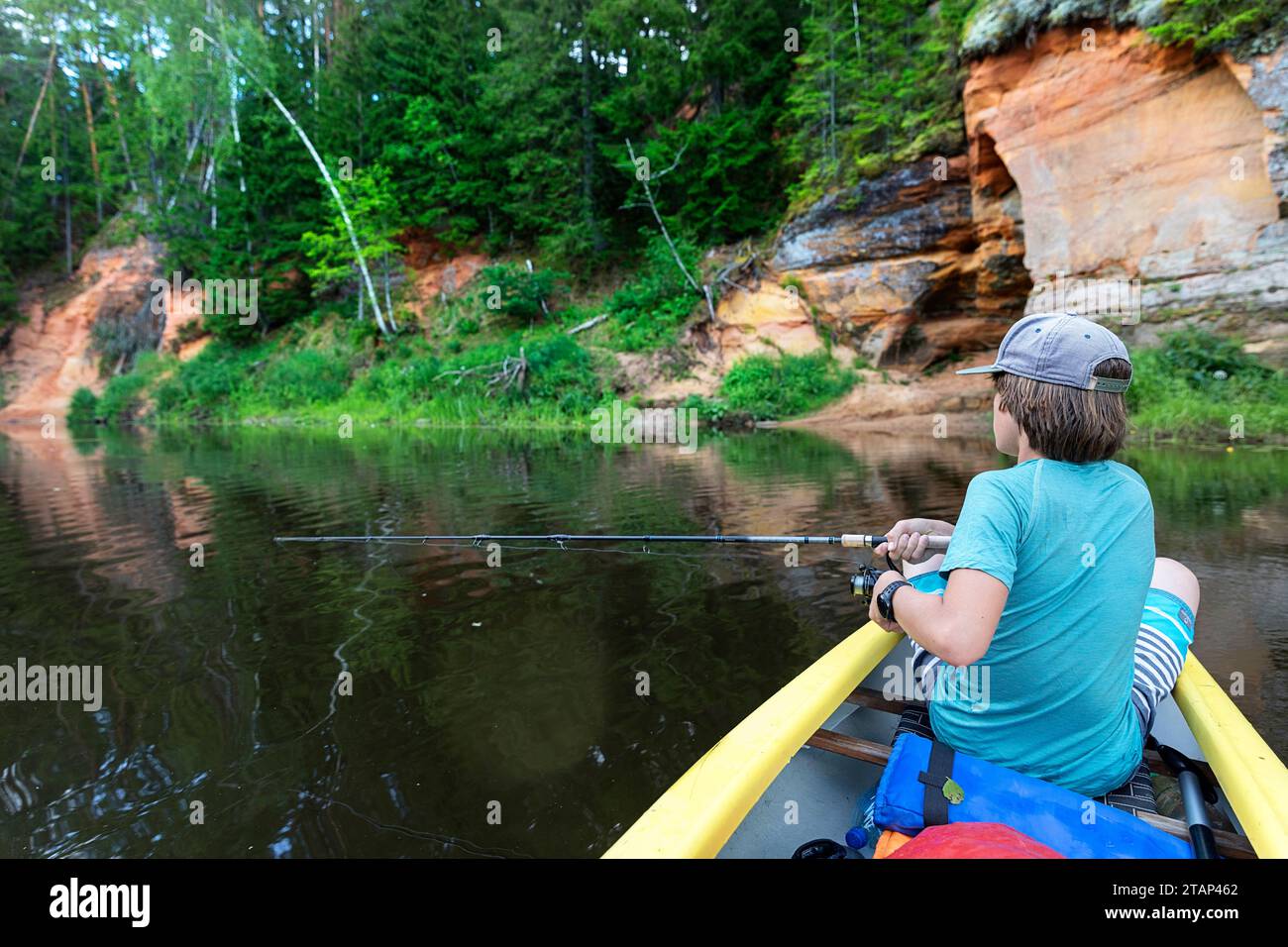 Tourist fishing while on a canoe, boat trip on Salaca river, exploring ...