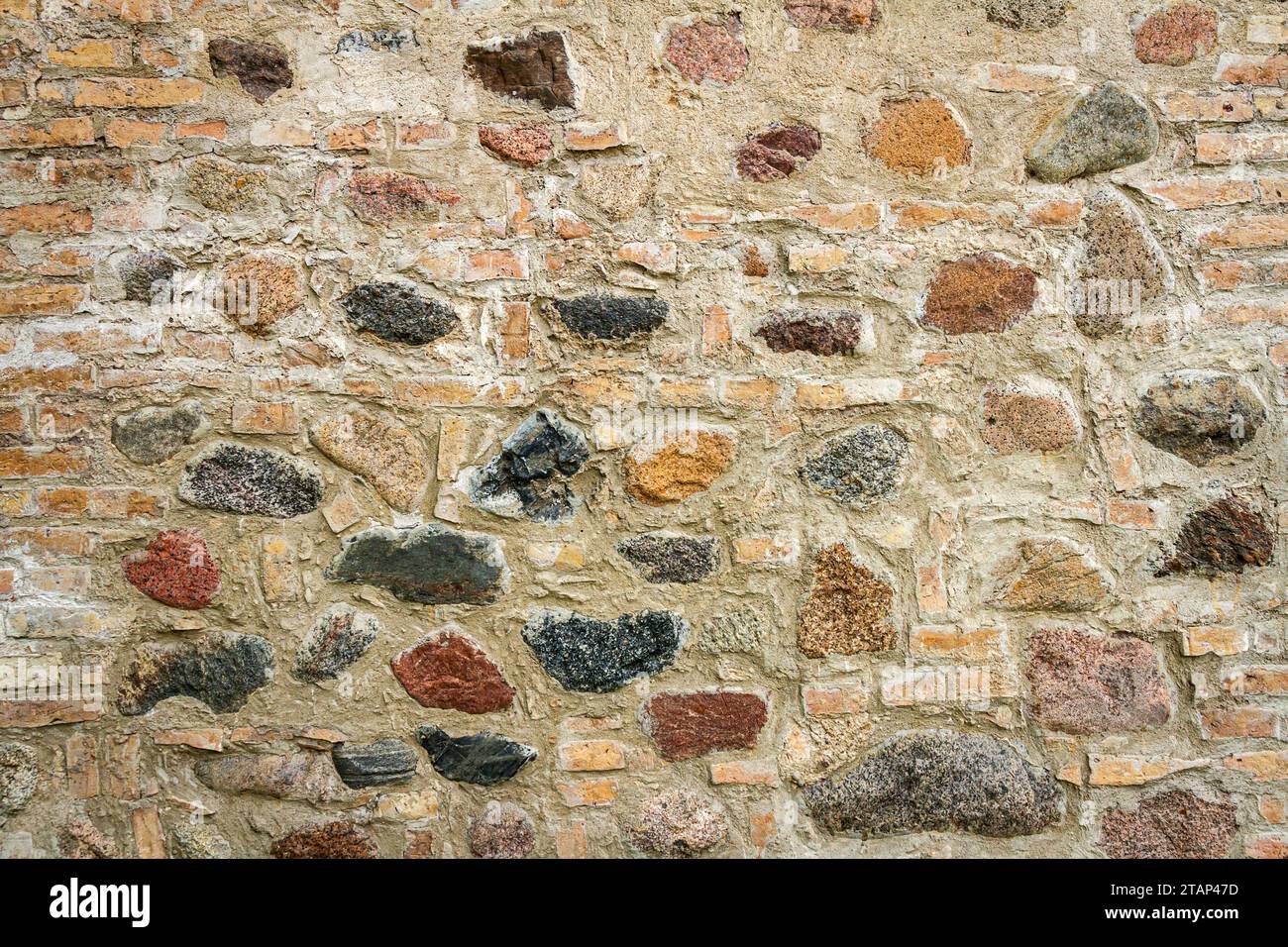 Wall texture with pieces of old bricks mixed with exposed round stones ...