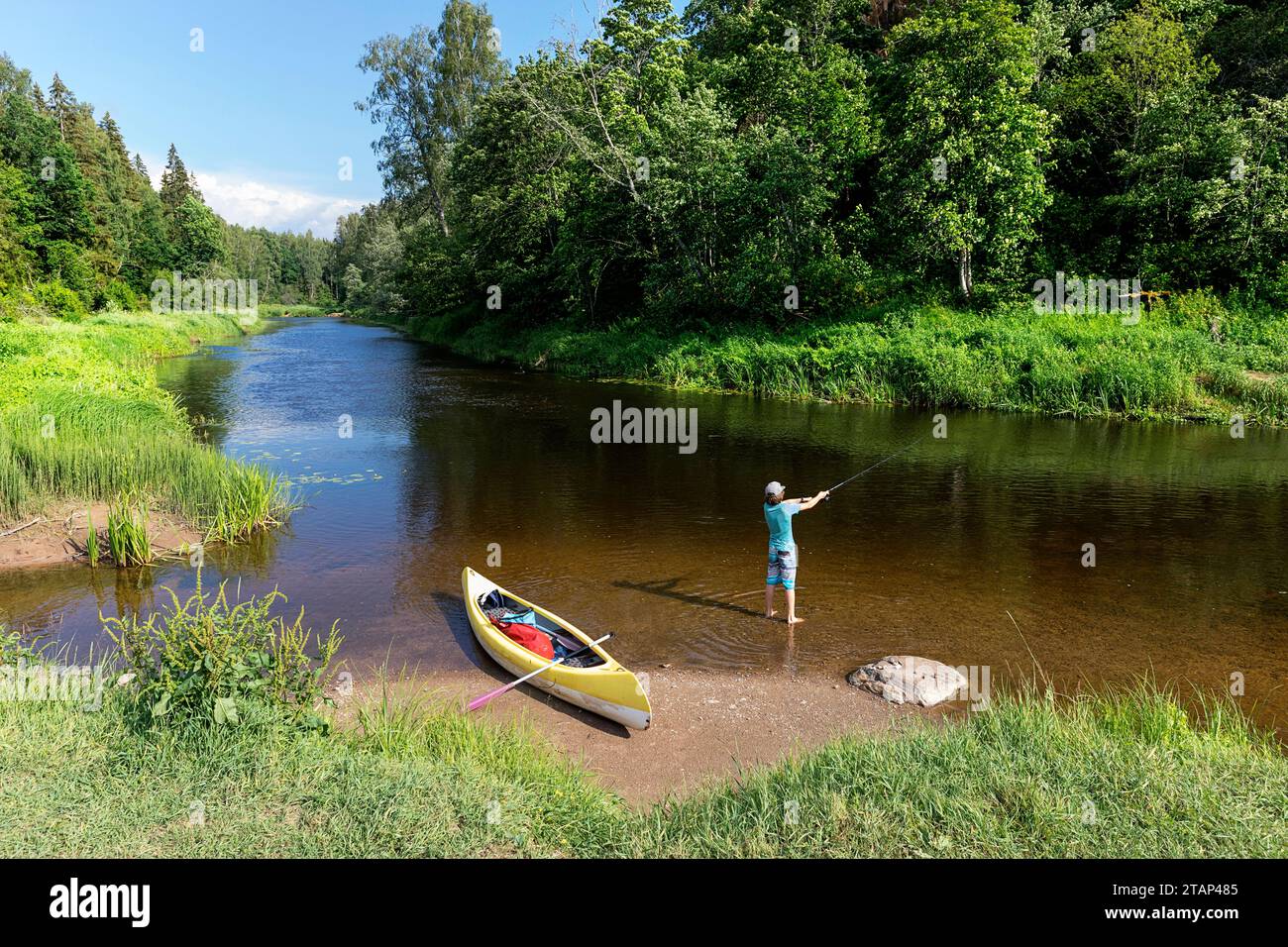 Tourist fishing while on a canoe, boat trip on Salaca river, exploring ...