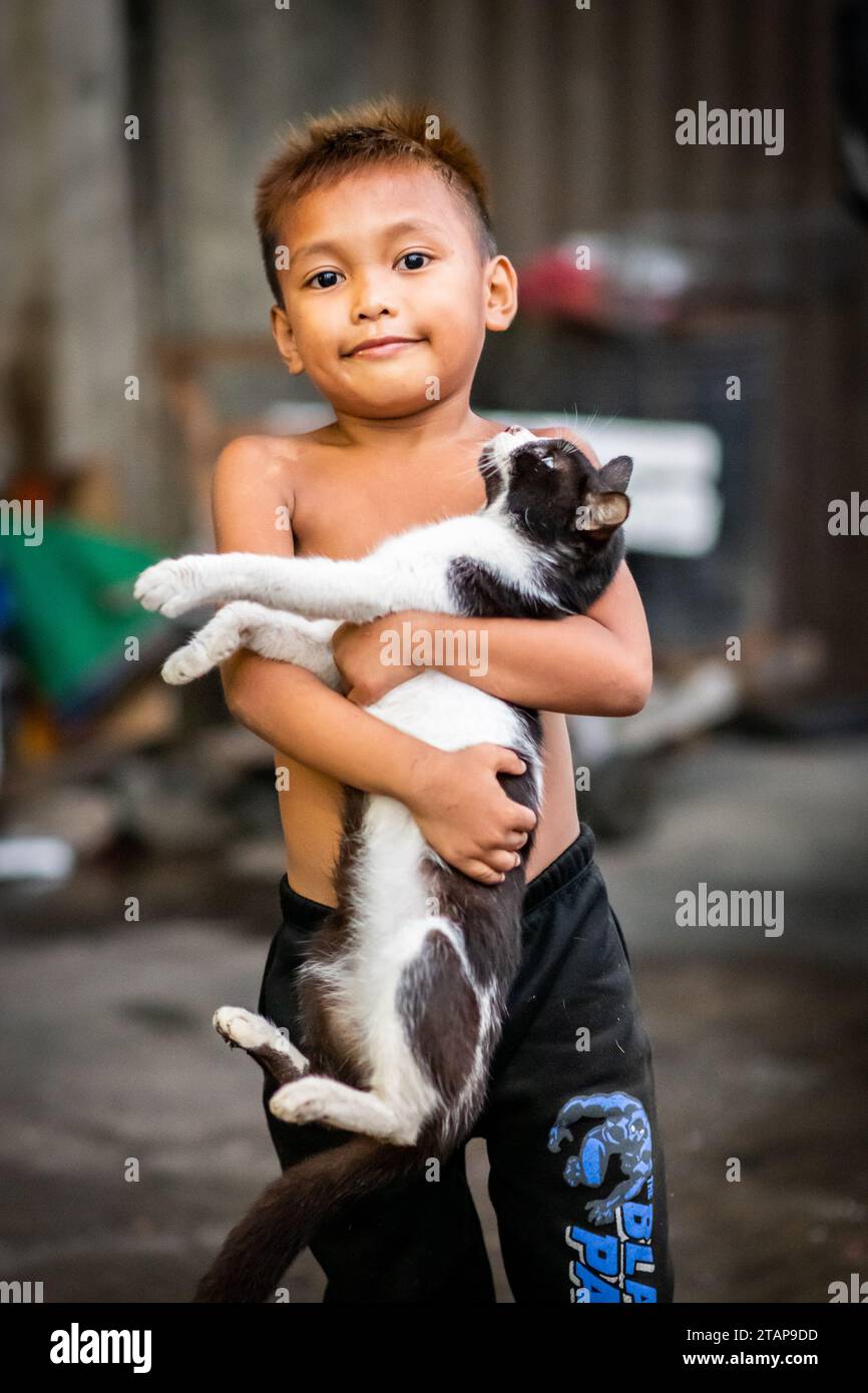 A cute young filipino boy holds his pet cat in Manila, The Philippines ...