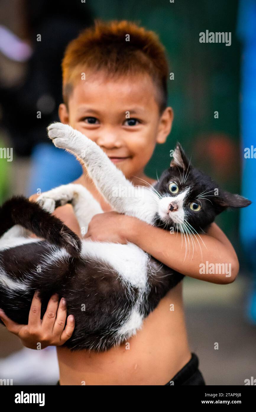 A cute young filipino boy holds his pet cat in Manila, The Philippines ...