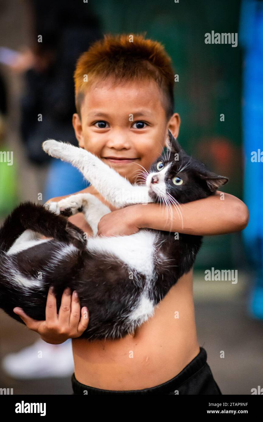A cute young filipino boy holds his pet cat in Manila, The Philippines ...